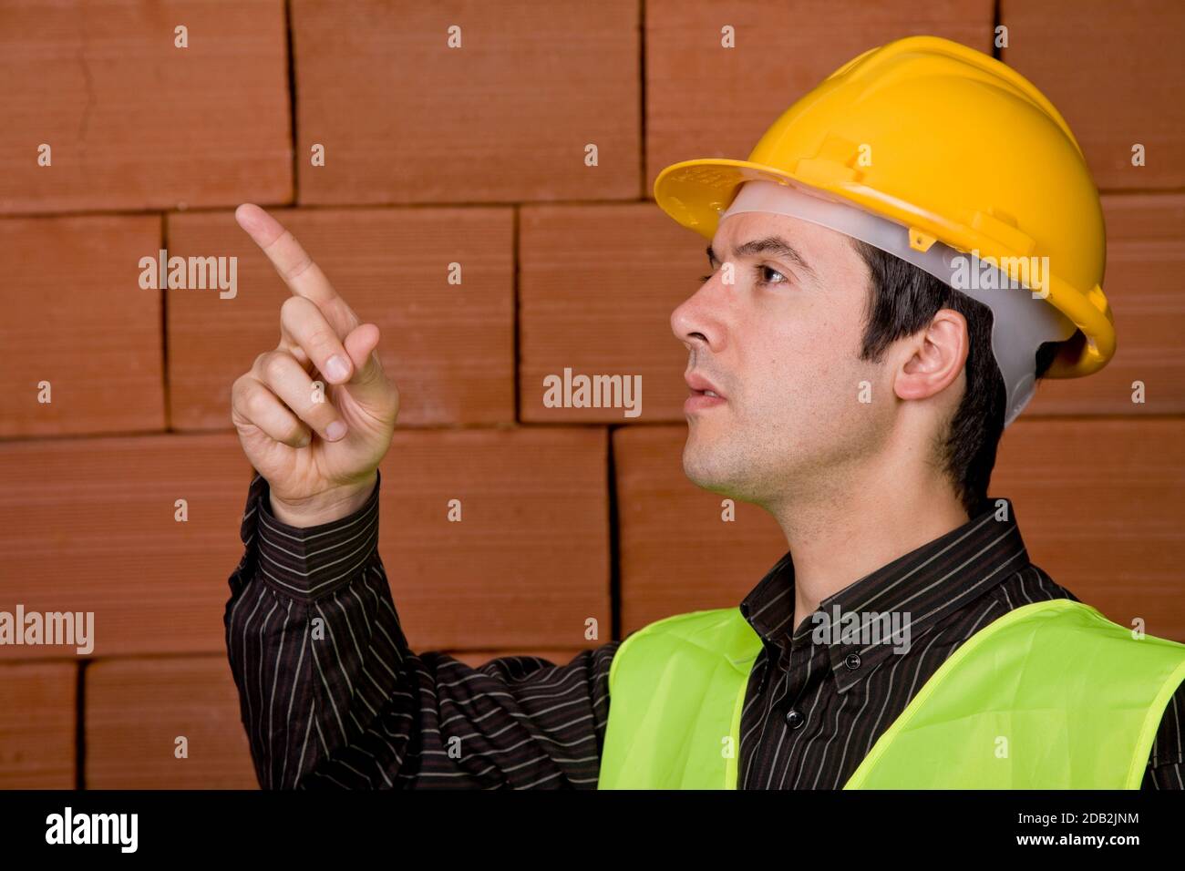 engineer with white hat and a brick wall as background Stock Photo - Alamy