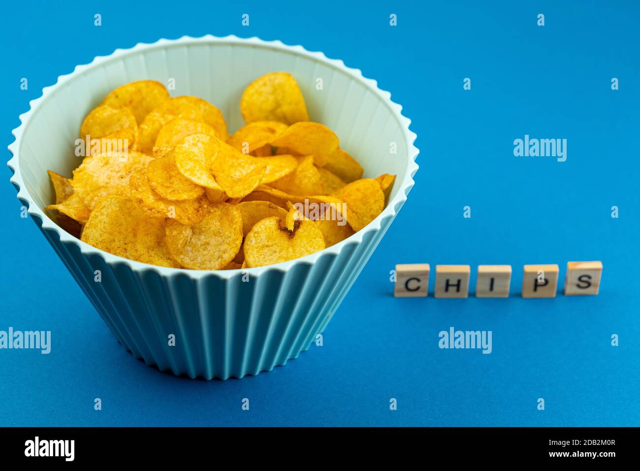 The word chips is lined with wooden letters. A bowl of potato chips on ...