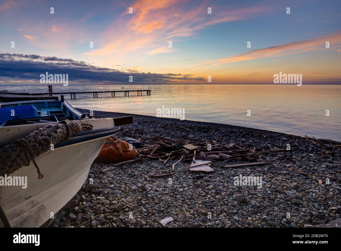 Beautiful landscape with a boat by the sea at sunset Stock Photo - Alamy