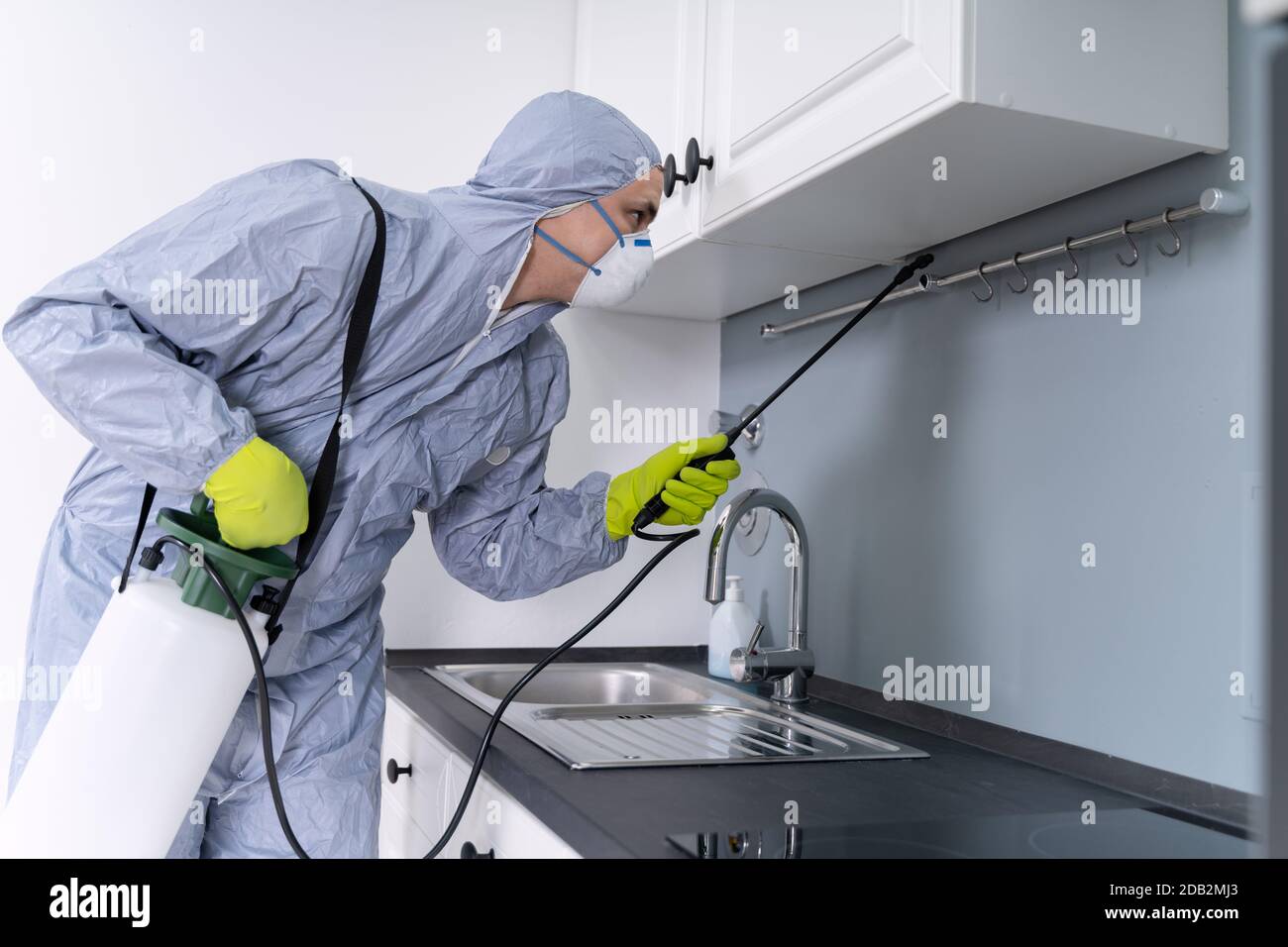 Side View Of Exterminator In Workwear Spraying Pesticide In Kitchen ...