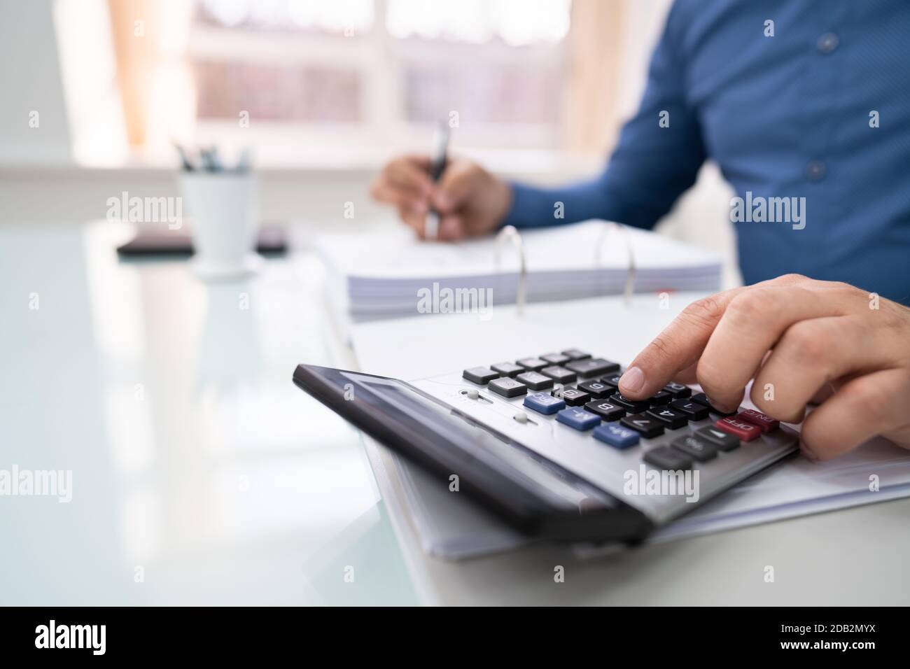 Young businessman holding calculator checking hi-res stock photography ...