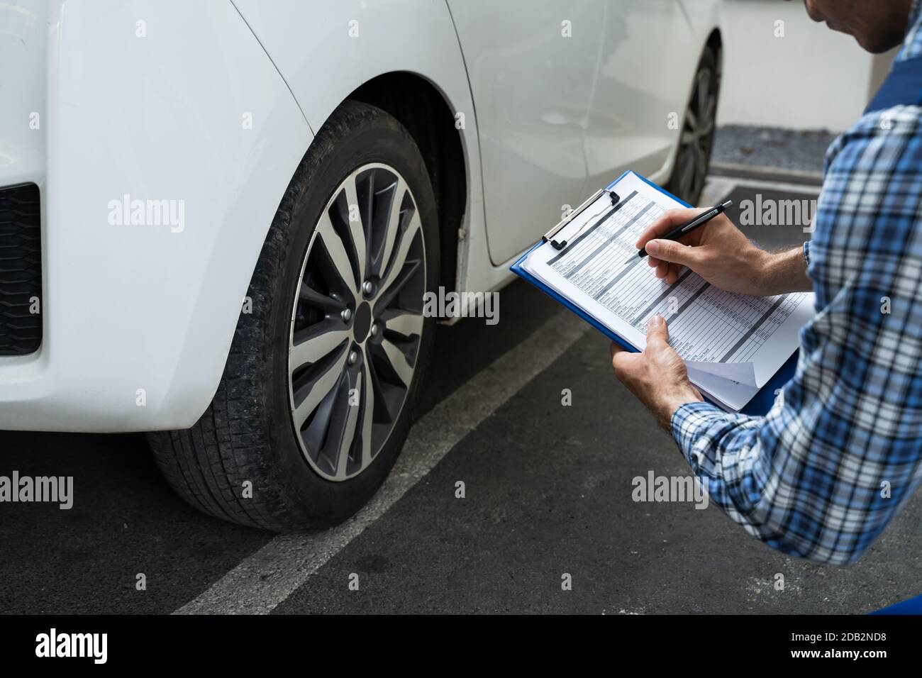 Young Mechanic Writing On Clipboard White Examining Car Wheel Stock ...