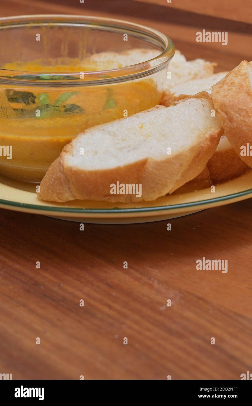 Bowl of spicy vegetarian curry with french loaf or baguette, at a ...