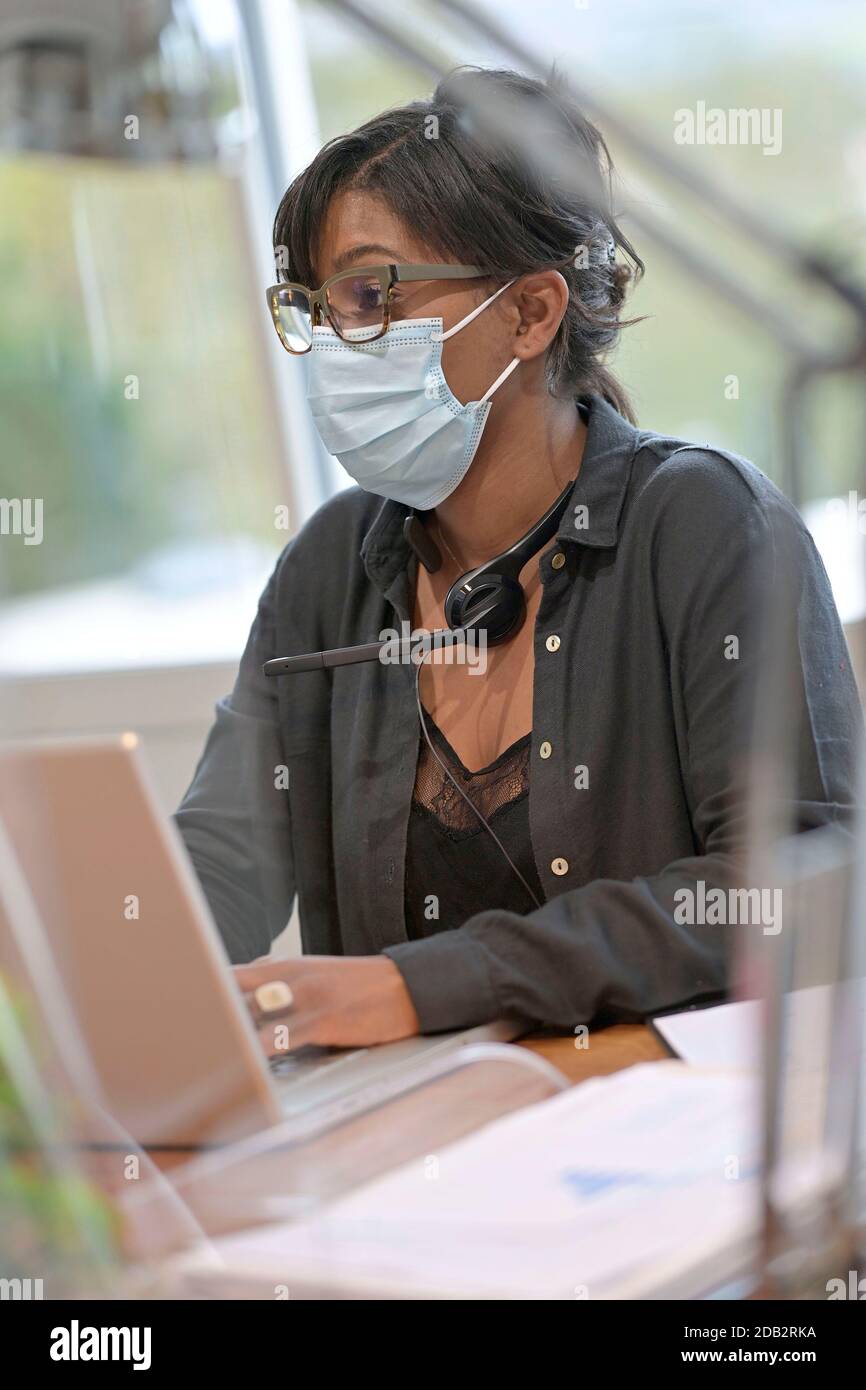 Office worker wearing surgical face mask in open space area Stock Photo ...