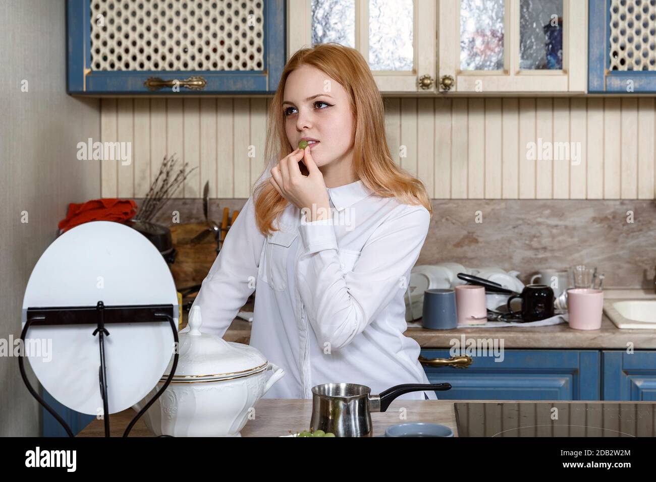beautiful red-haired girl in the kitchen eating grapes Stock Photo - Alamy