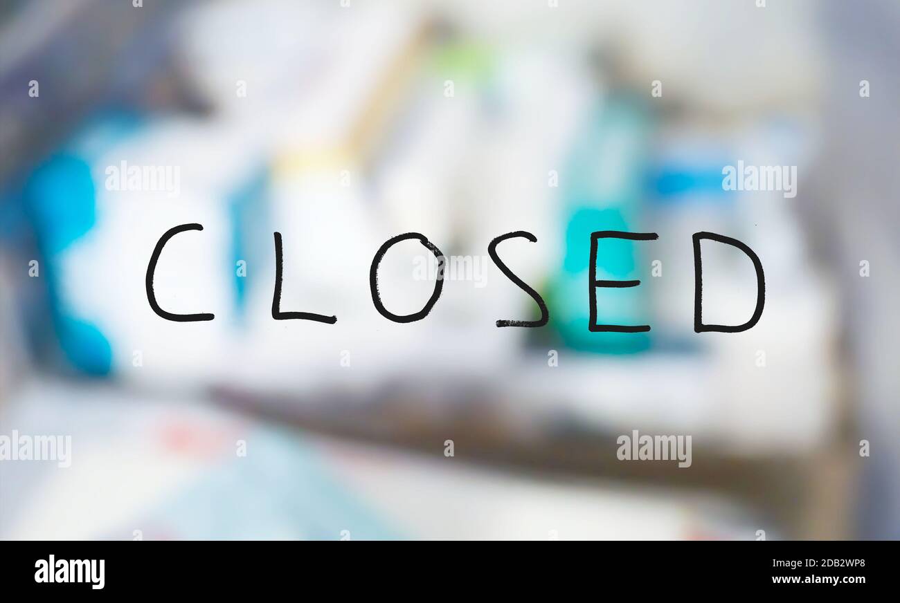 Handwritten closed sign on a shop window with blurred products in the ...