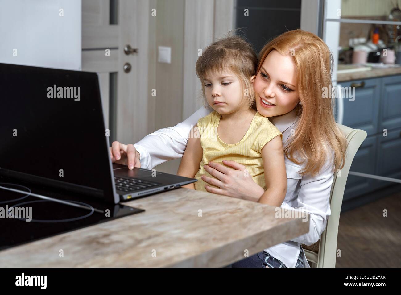Woman and cute child using laptop. the child looks at the screen with ...