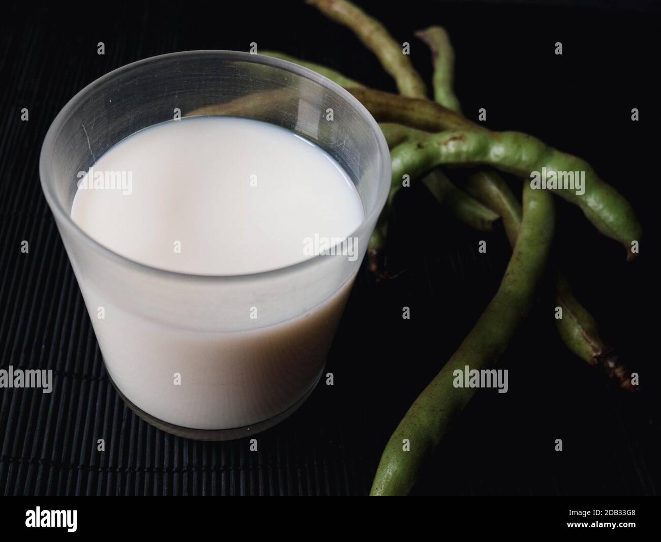 A top view shot of a glass of pea milk and peas on the dark surface ...