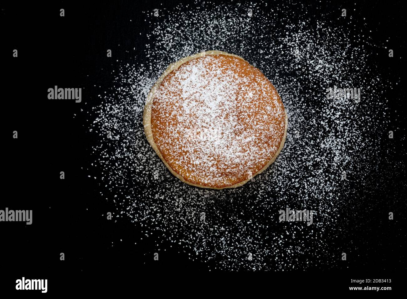 Traditional German Krapfen or doughnut with powder sugar on black ...