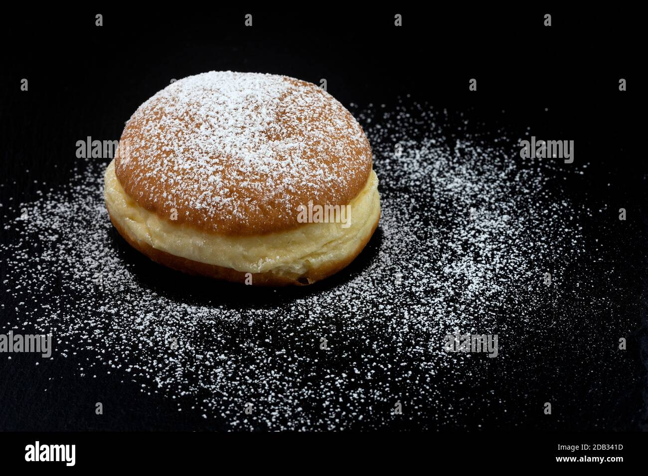 Traditional German Krapfen or doughnut with powder sugar on black ...