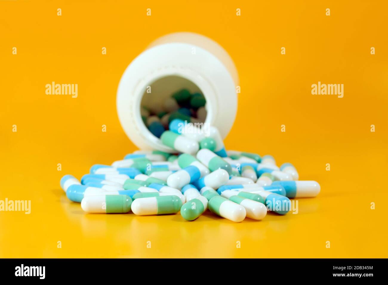 pill spilling isolated on yellow background Stock Photo - Alamy