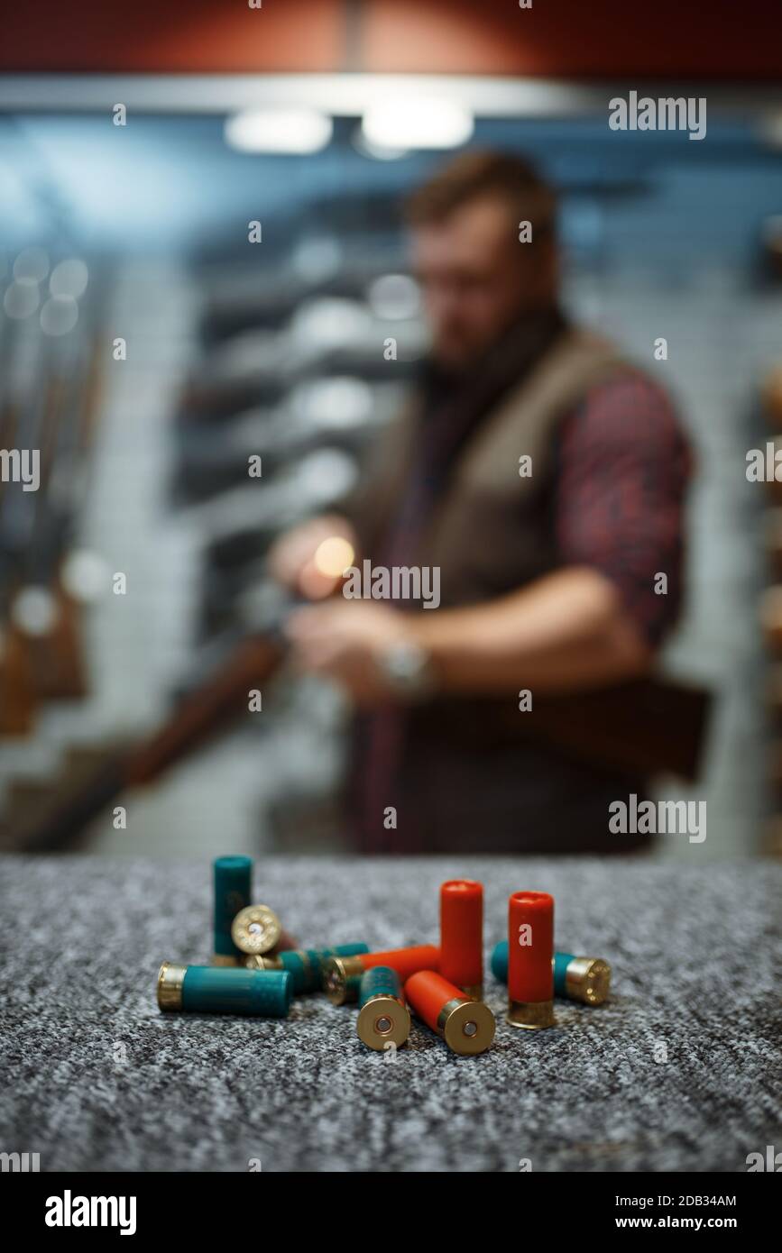 Ammo on counter, man loads a rifle on background, gun shop. Euqipment ...