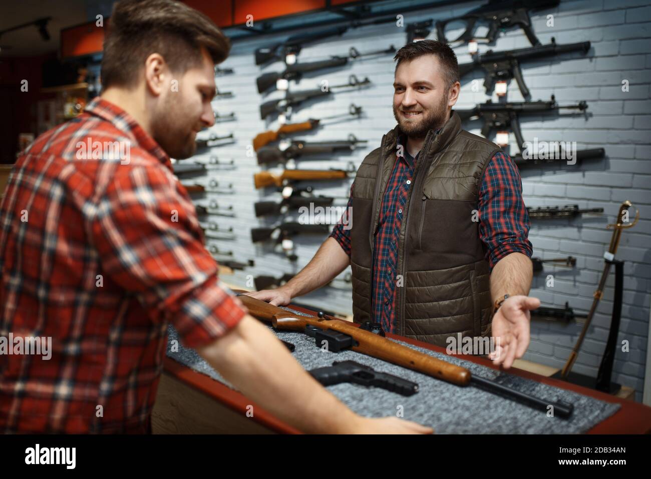 Man and owner choosing rifle in gun shop. Euqipment for hunters on ...