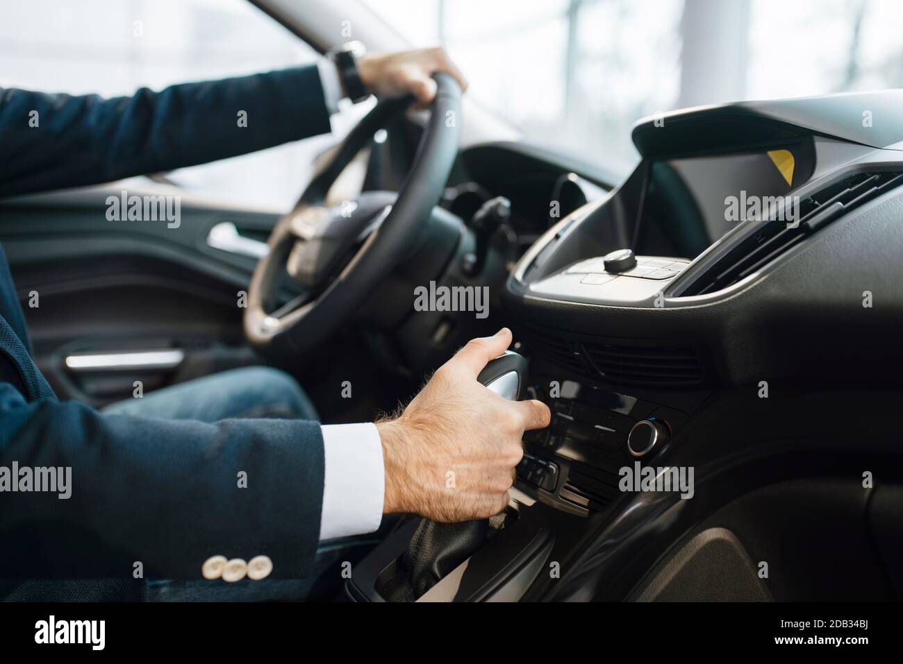 Man behind the wheel of new automobile in car dealership. Customer in ...