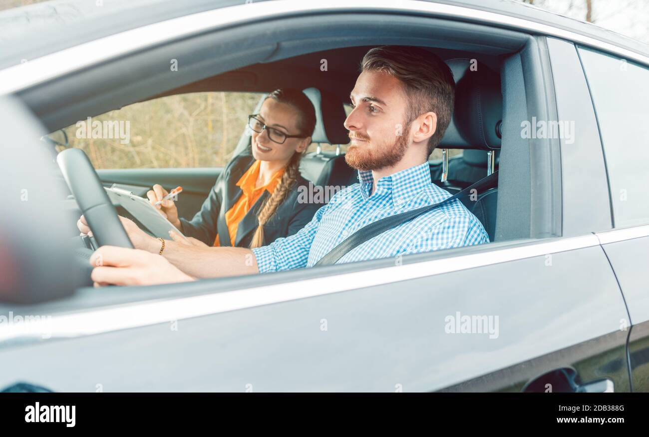 Driving instructor with student in school car teaching how to drive ...