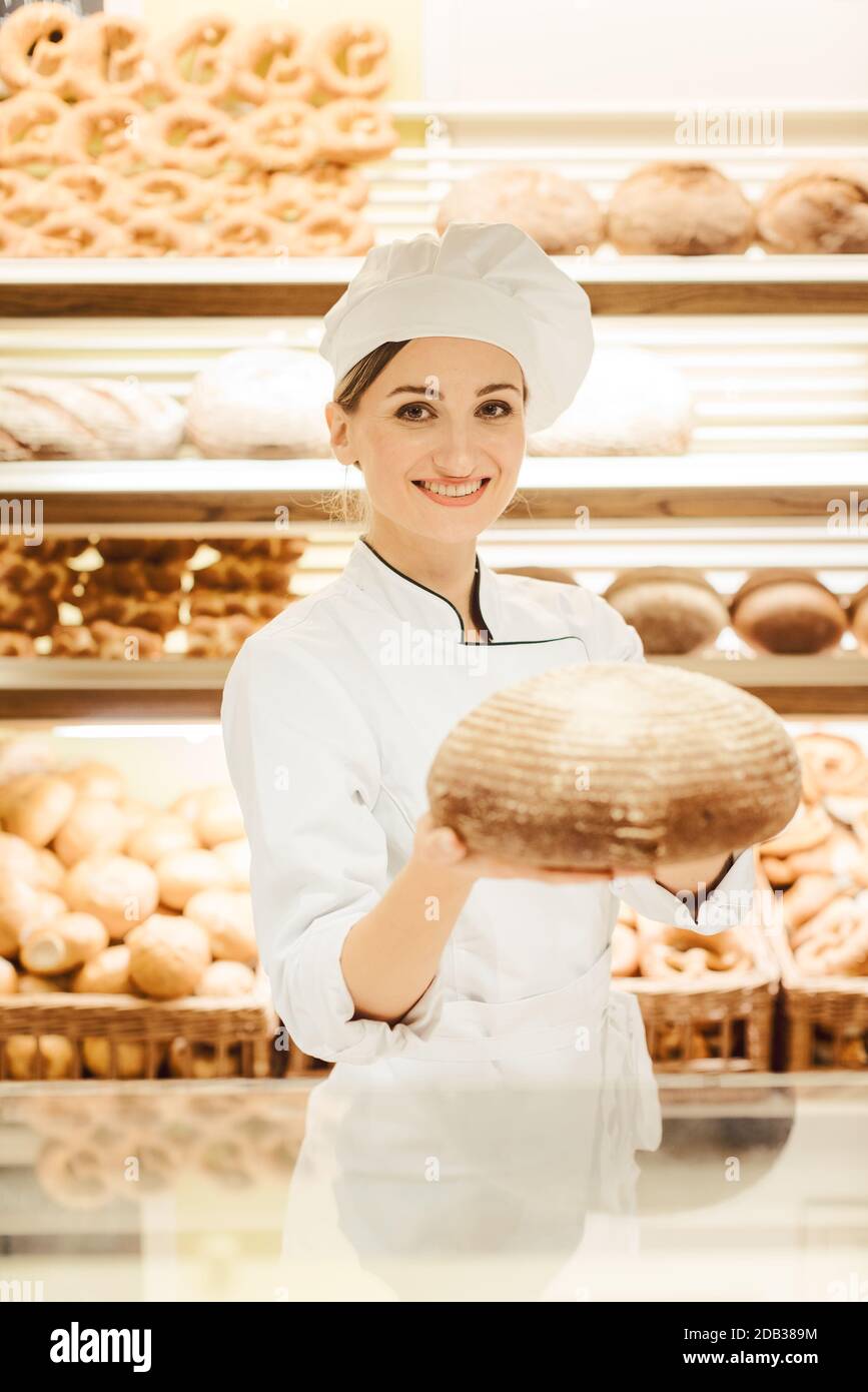 Beautiful woman selling bread in bakery offering a loaf Stock Photo - Alamy