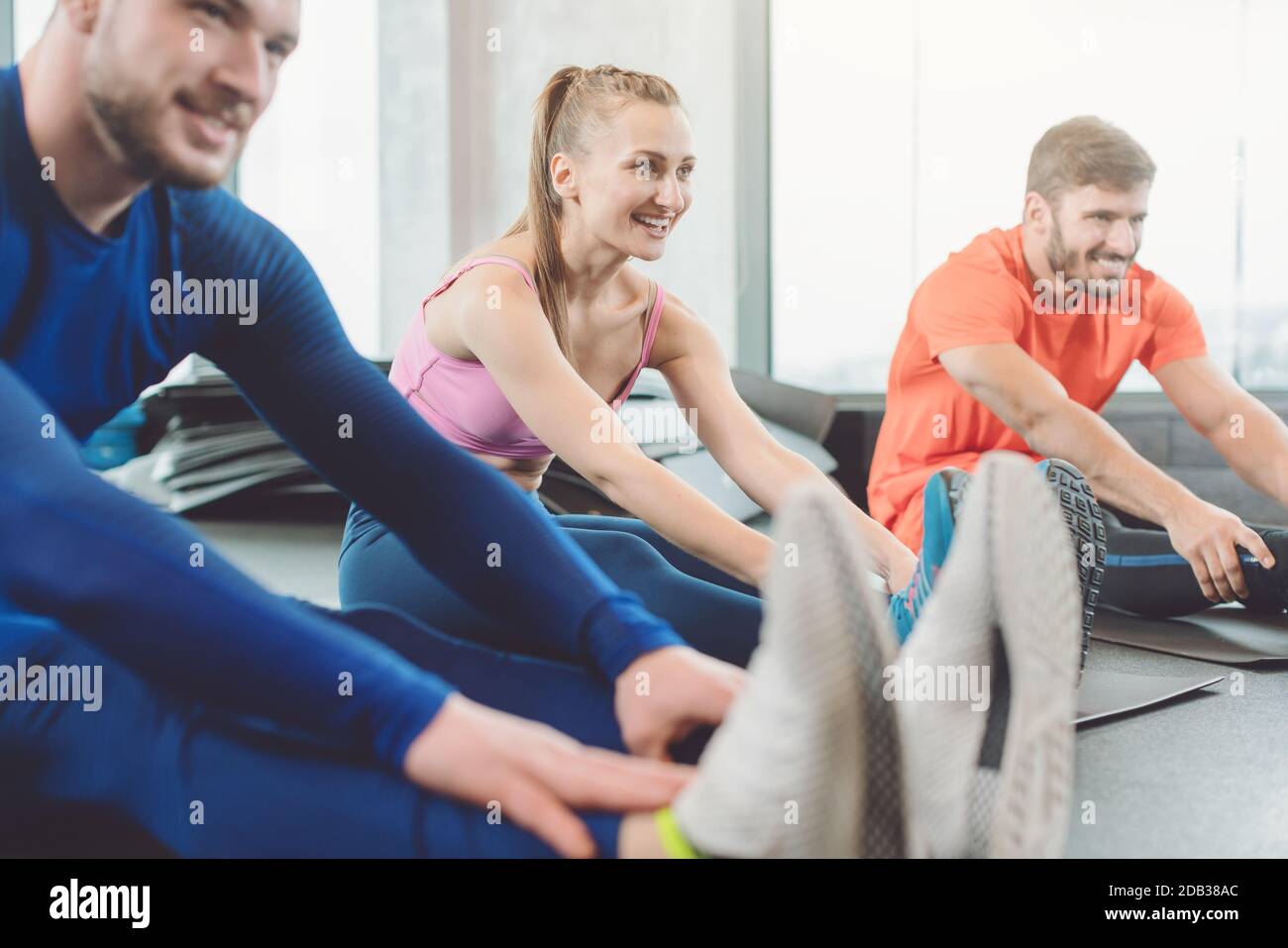 Group in fitness class doing gymnastics and stretching in modern gym ...