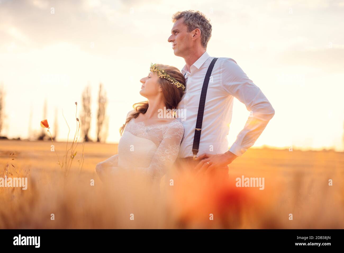 Wedding couple, bride and groom, during sunset in rural setting looking ...