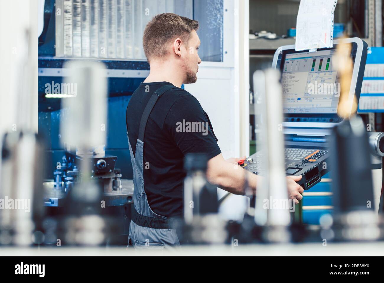 Worker in industrial workshop programming a cnc machine Stock Photo - Alamy