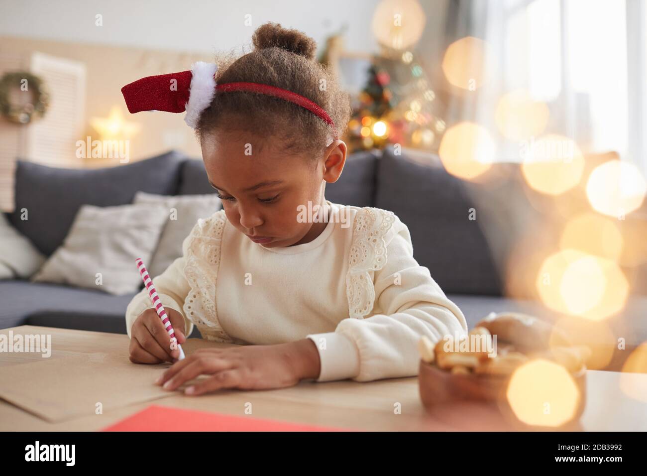 Close up portrait of cute African-American girl writing letter to Santa ...