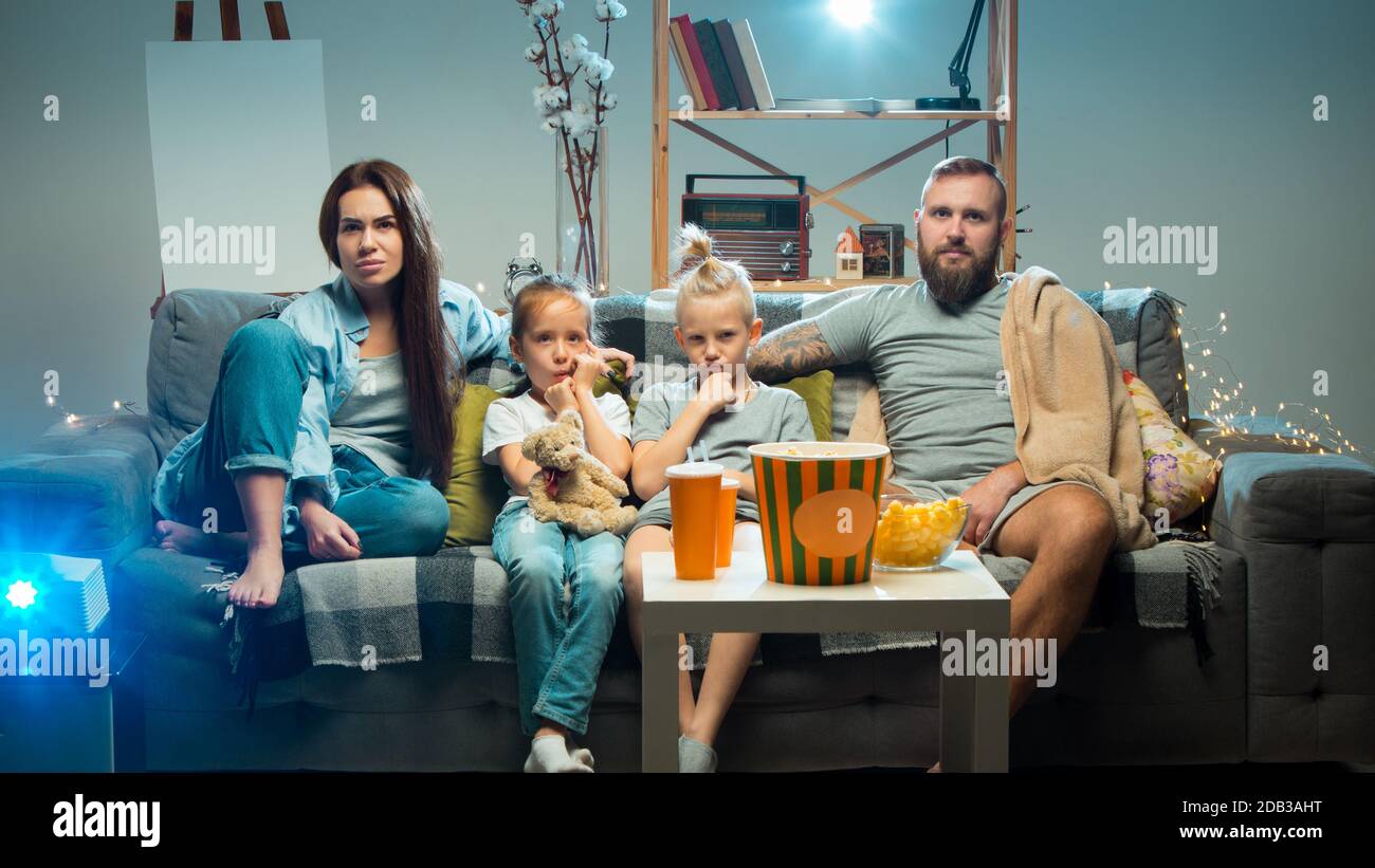 Enjoy. Happy family watching projector, TV, movies with popcorn and ...