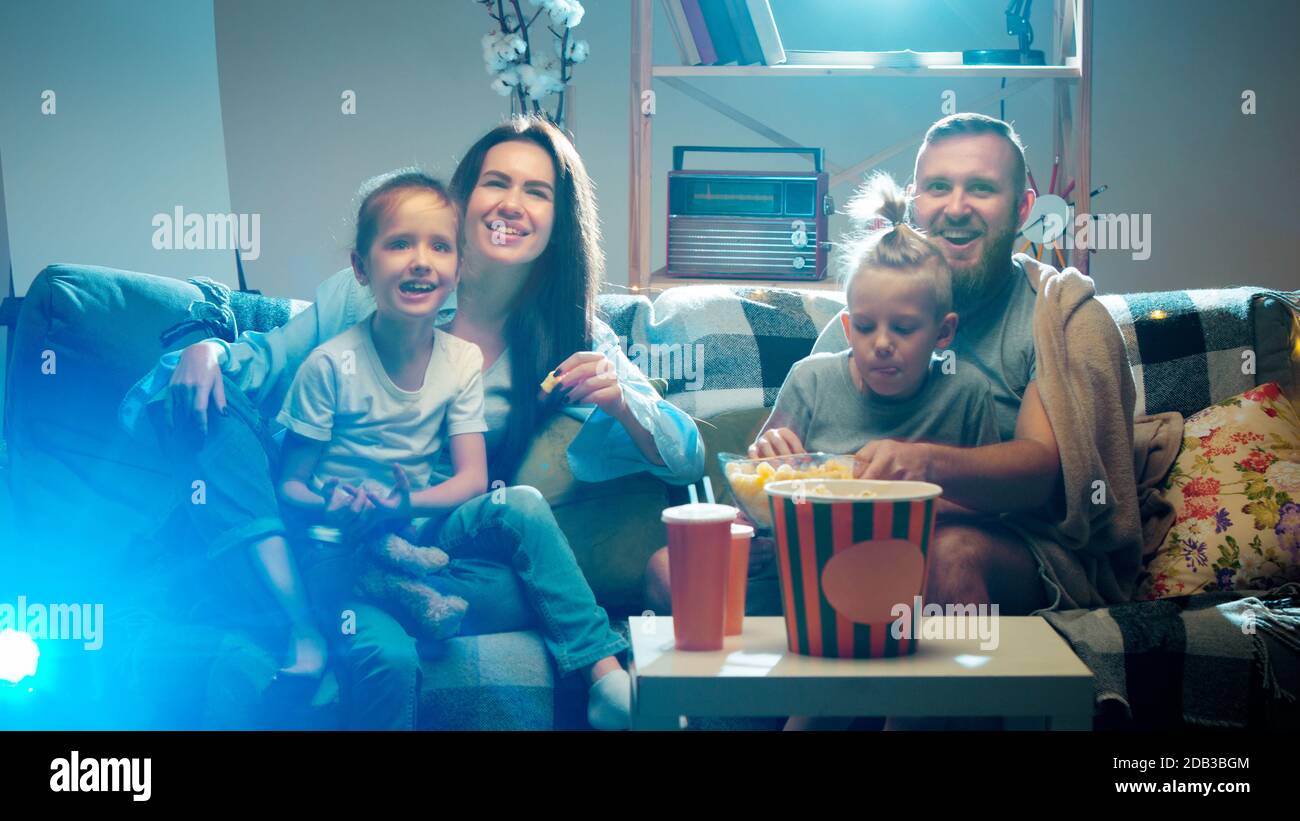 Enjoy. Happy family watching projector, TV, movies with popcorn and ...