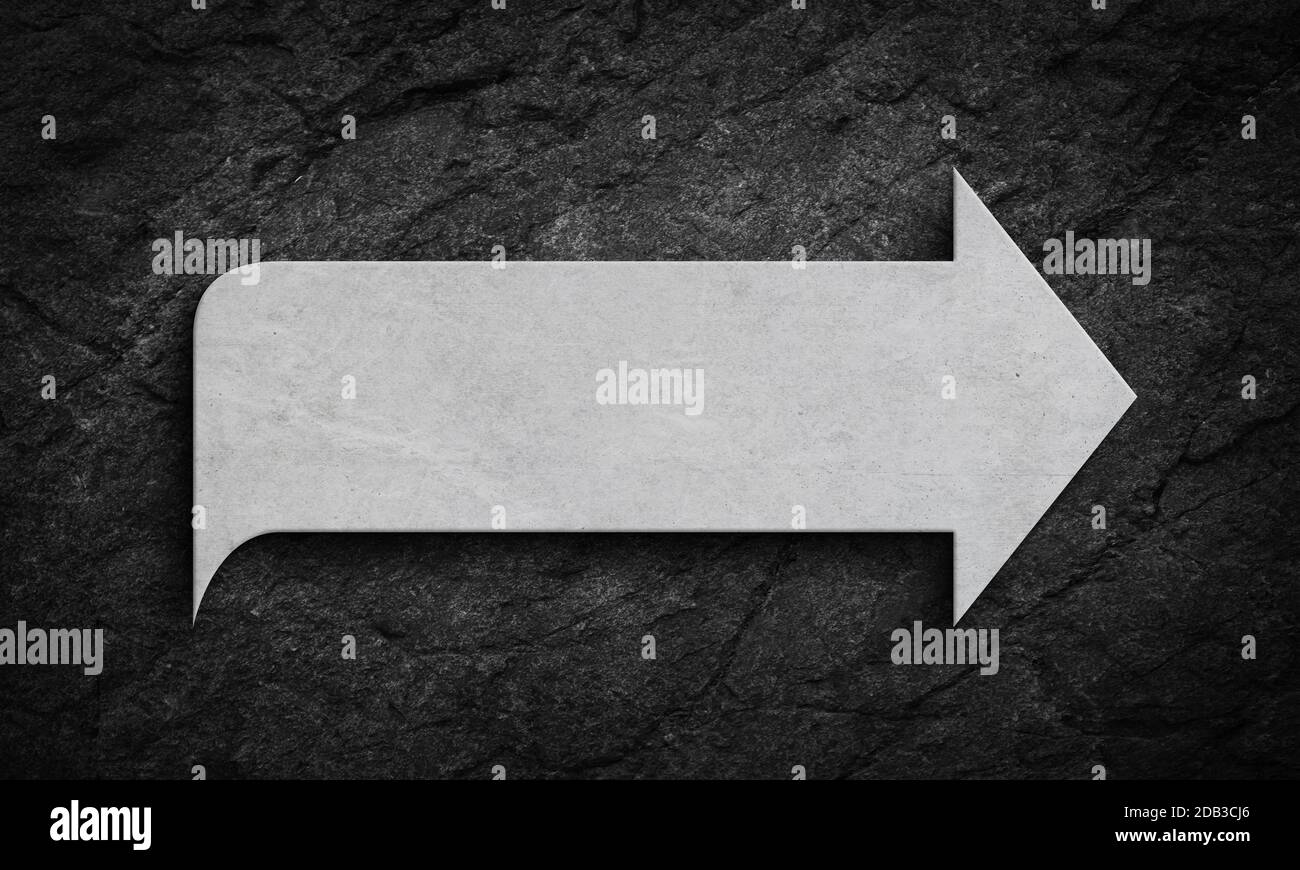 Blank white sign of stone with arrow shape in front of a solid dark ...