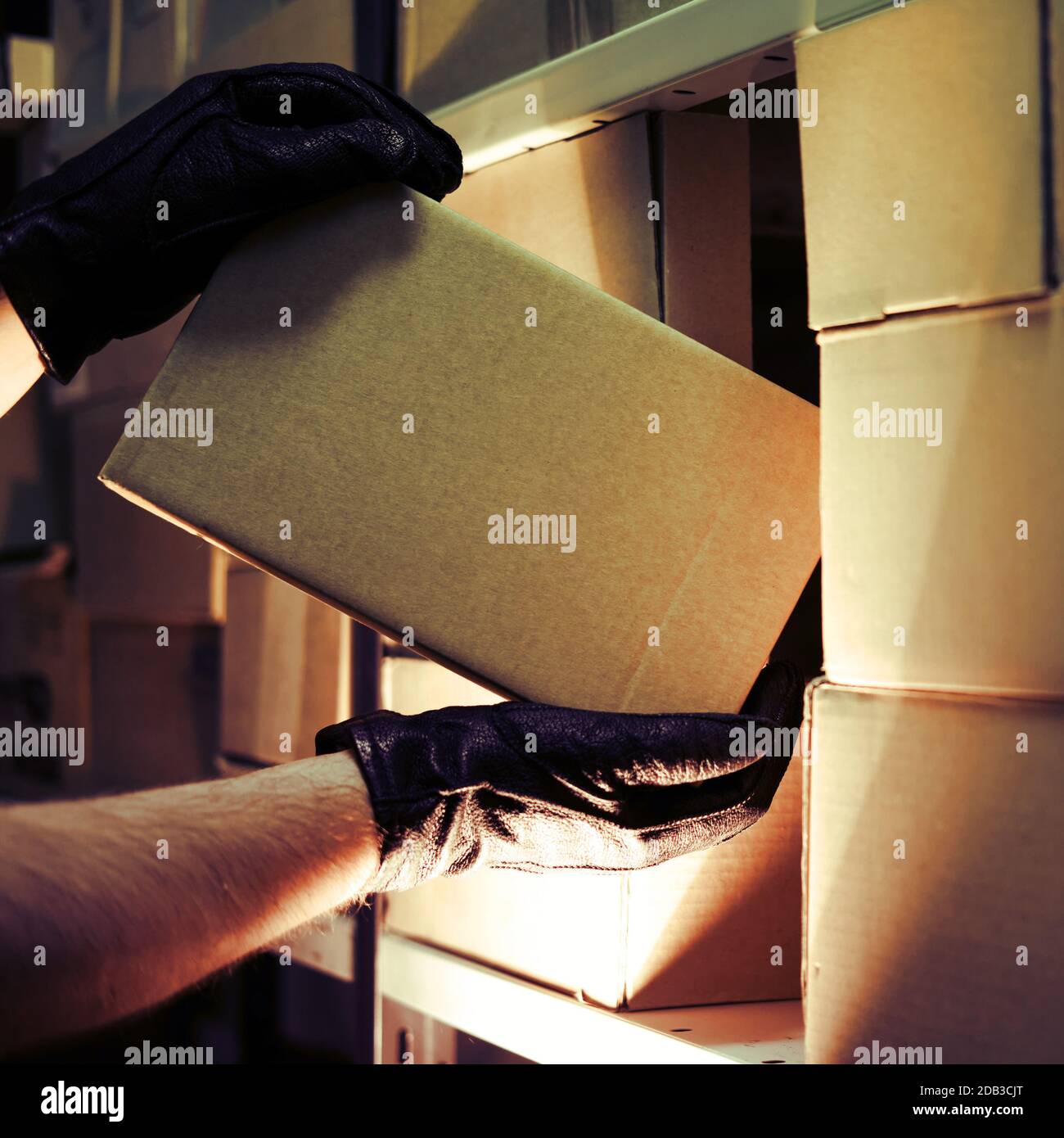 Theft of a box with a parcel in a warehouse. Man hands in gloves steal ...