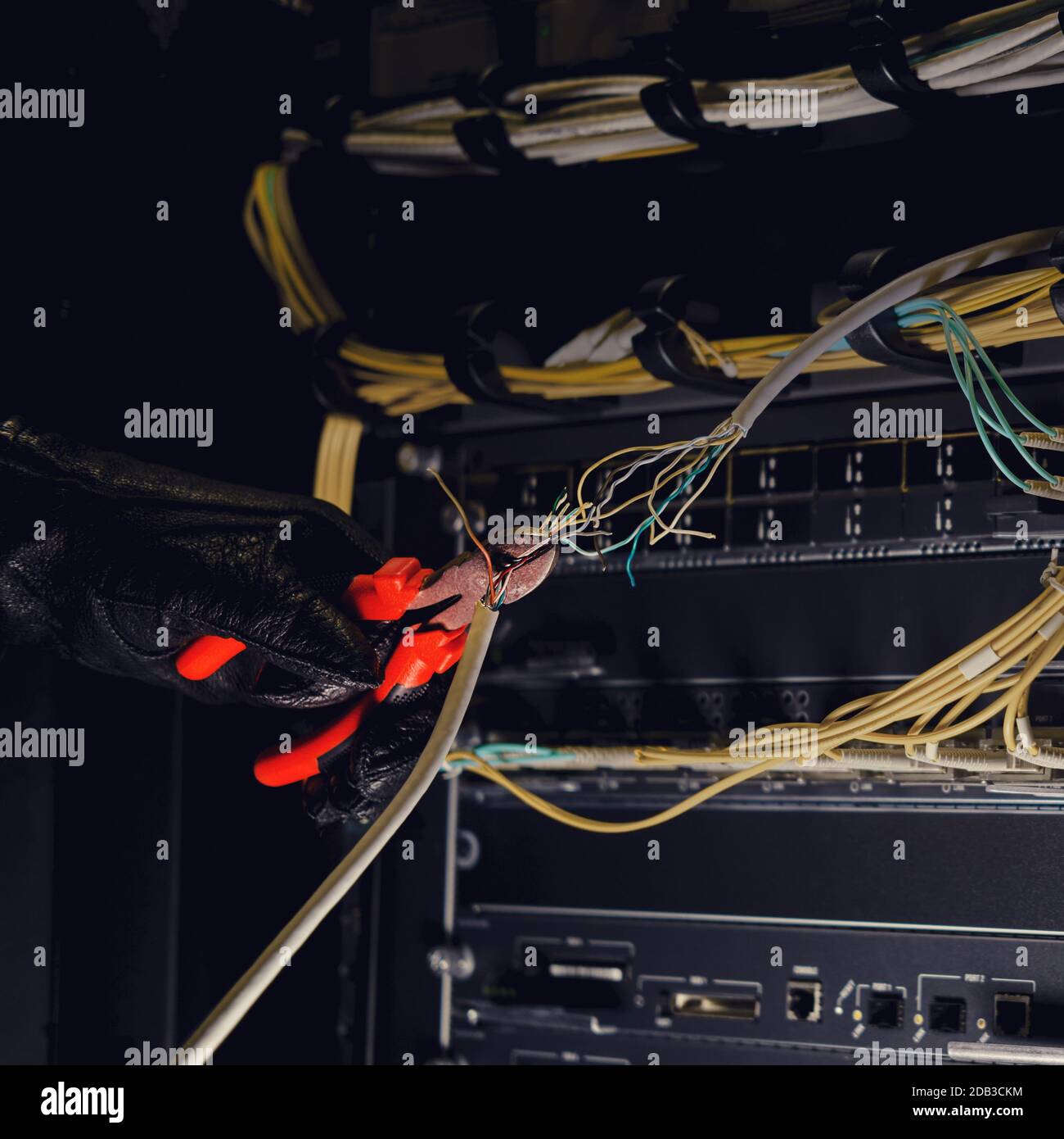 Hand with pliers bites the wires in the server room. Concept of ...