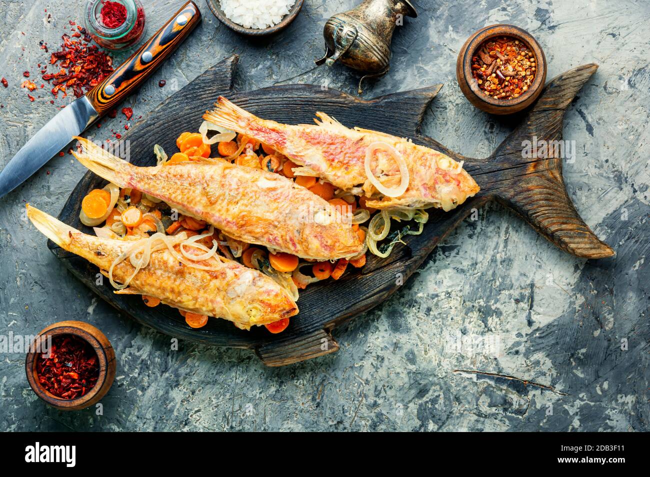 Mullet fish fried with horseradish rootsSpicy fry fish on cutting board ...