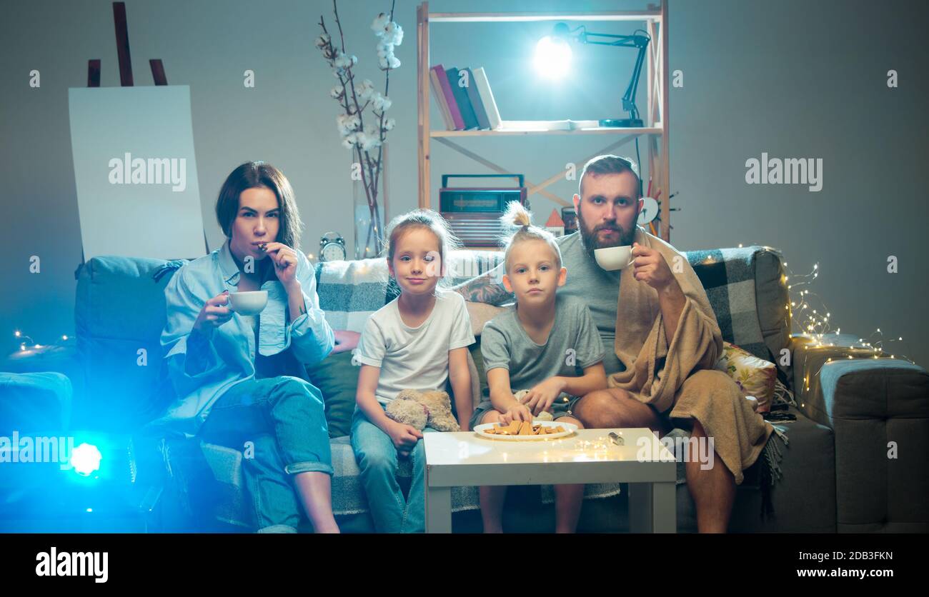 Togetherness. Happy family watching projector, TV, movies with popcorn ...
