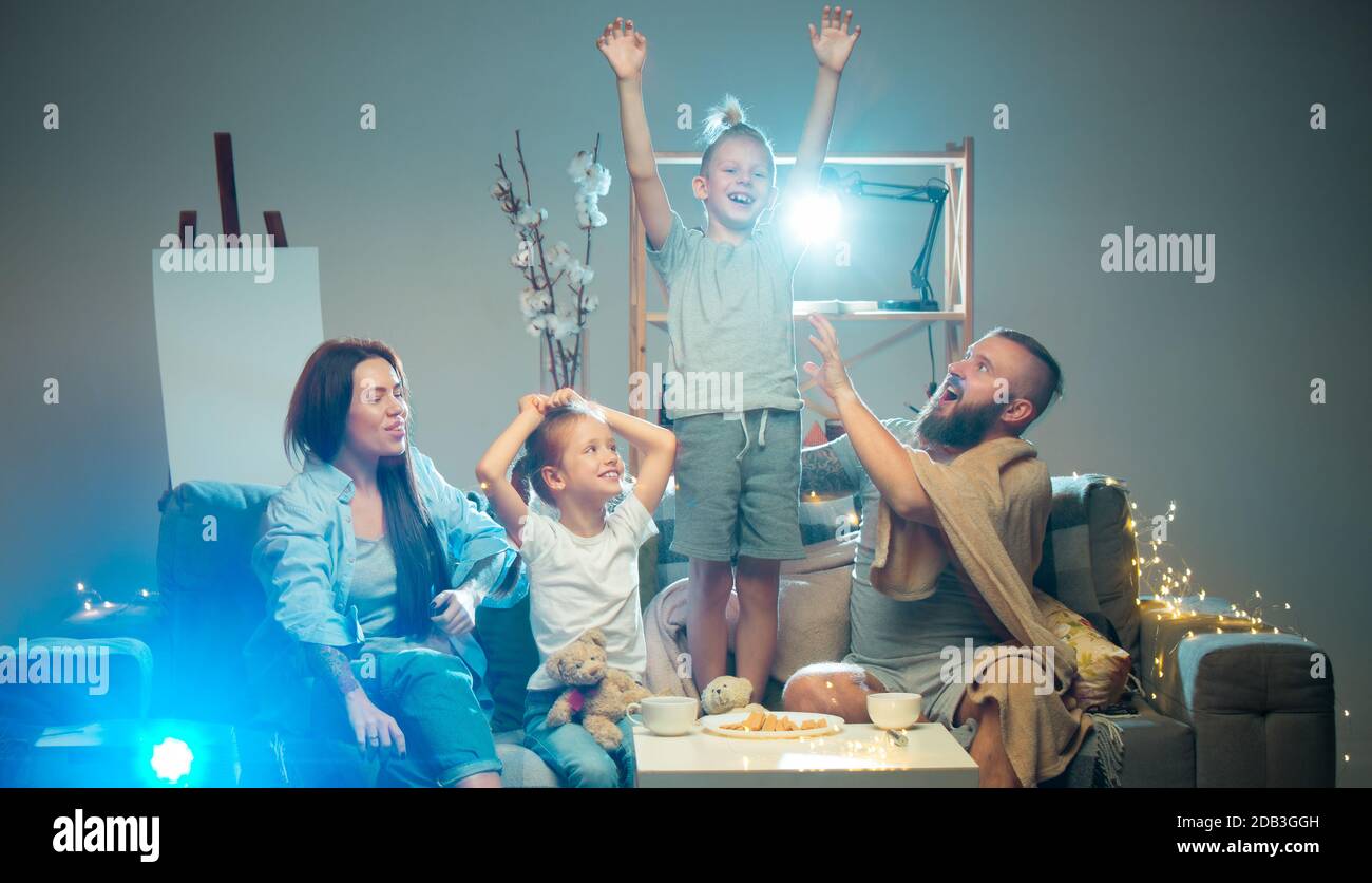 Fun. Happy family watching projector, TV, movies with popcorn and ...