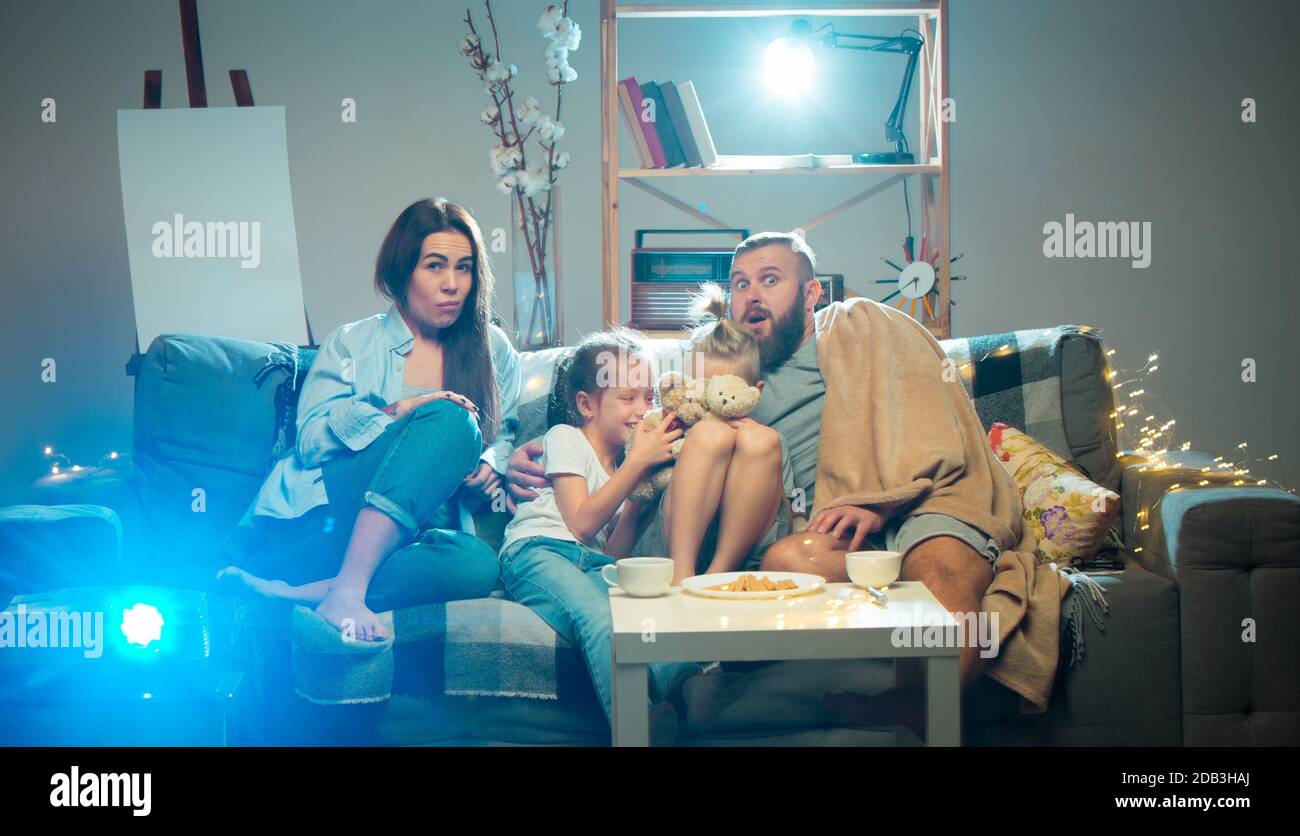 Fun. Happy family watching projector, TV, movies with popcorn and ...