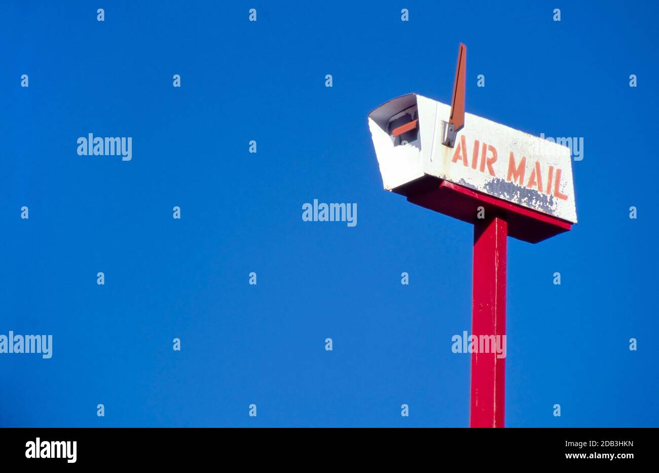 Air mail postbox with shipping delivery red flag against clear blue sky ...