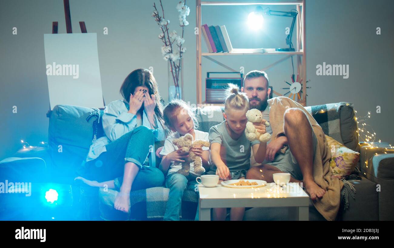 Night. Happy family watching projector, TV, movies with popcorn and ...