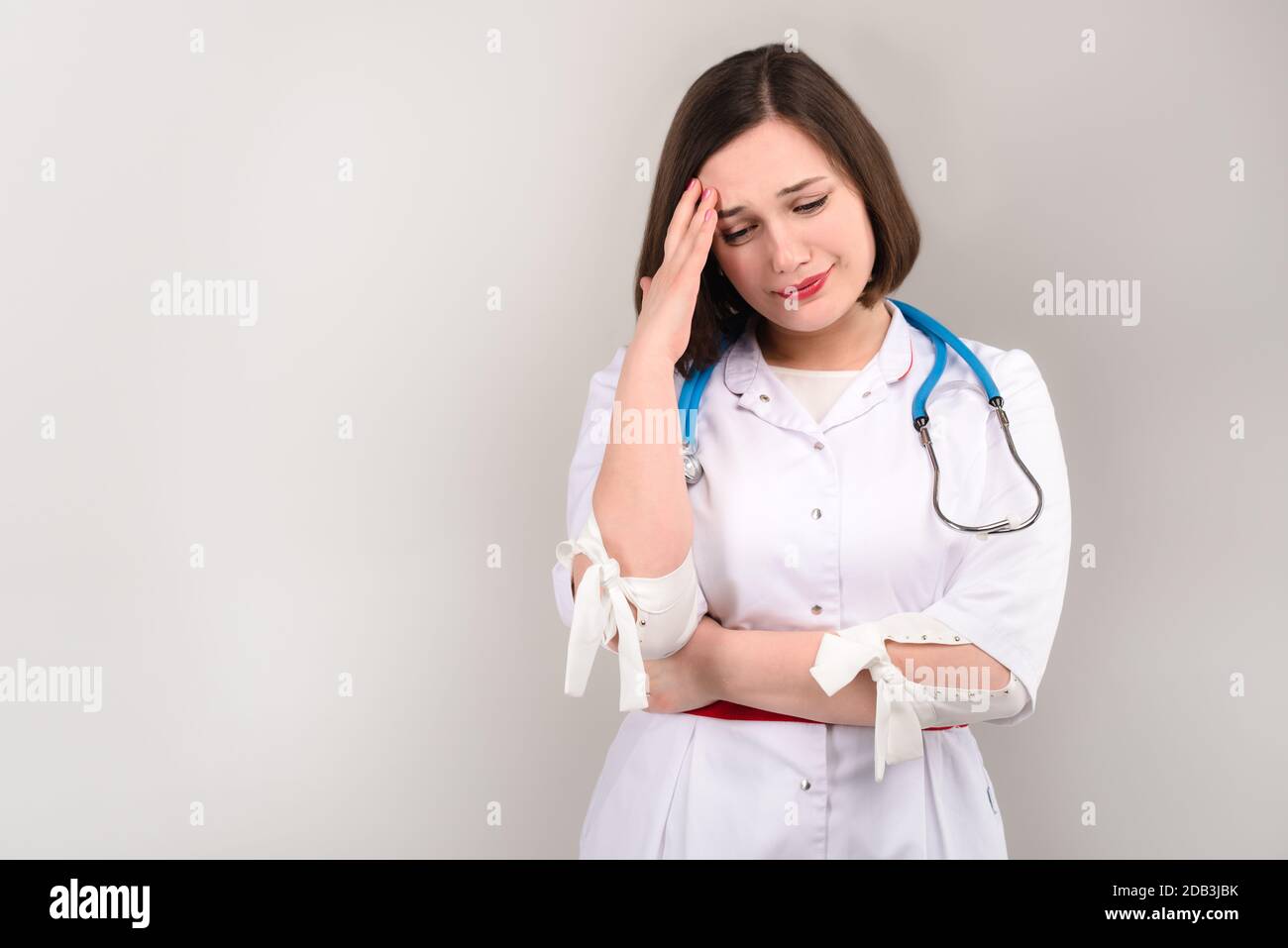 Portrait of beautiful young doctor with regretful face on light ...