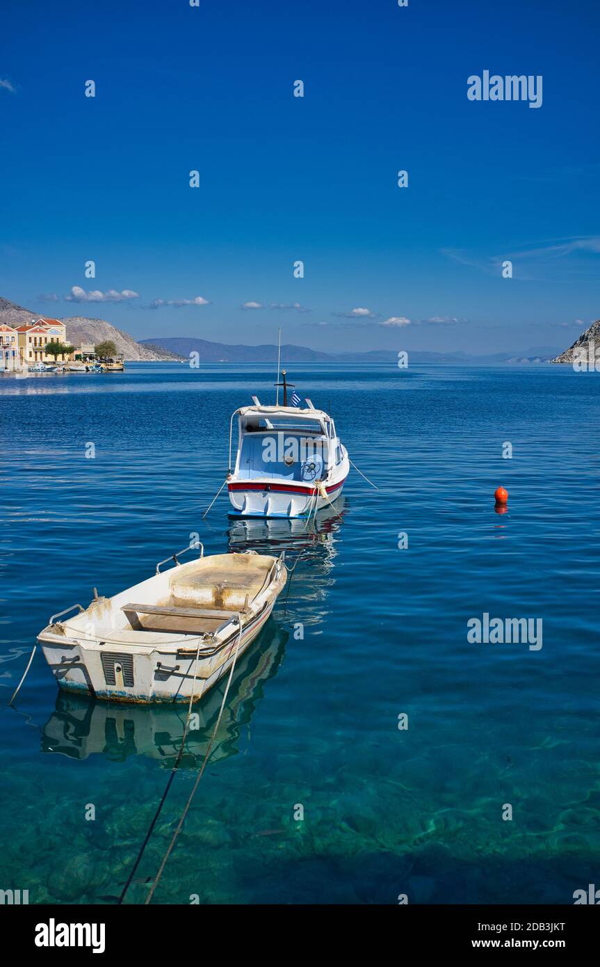A vertical shot of a seascape with a parked boat in Symi greek island ...