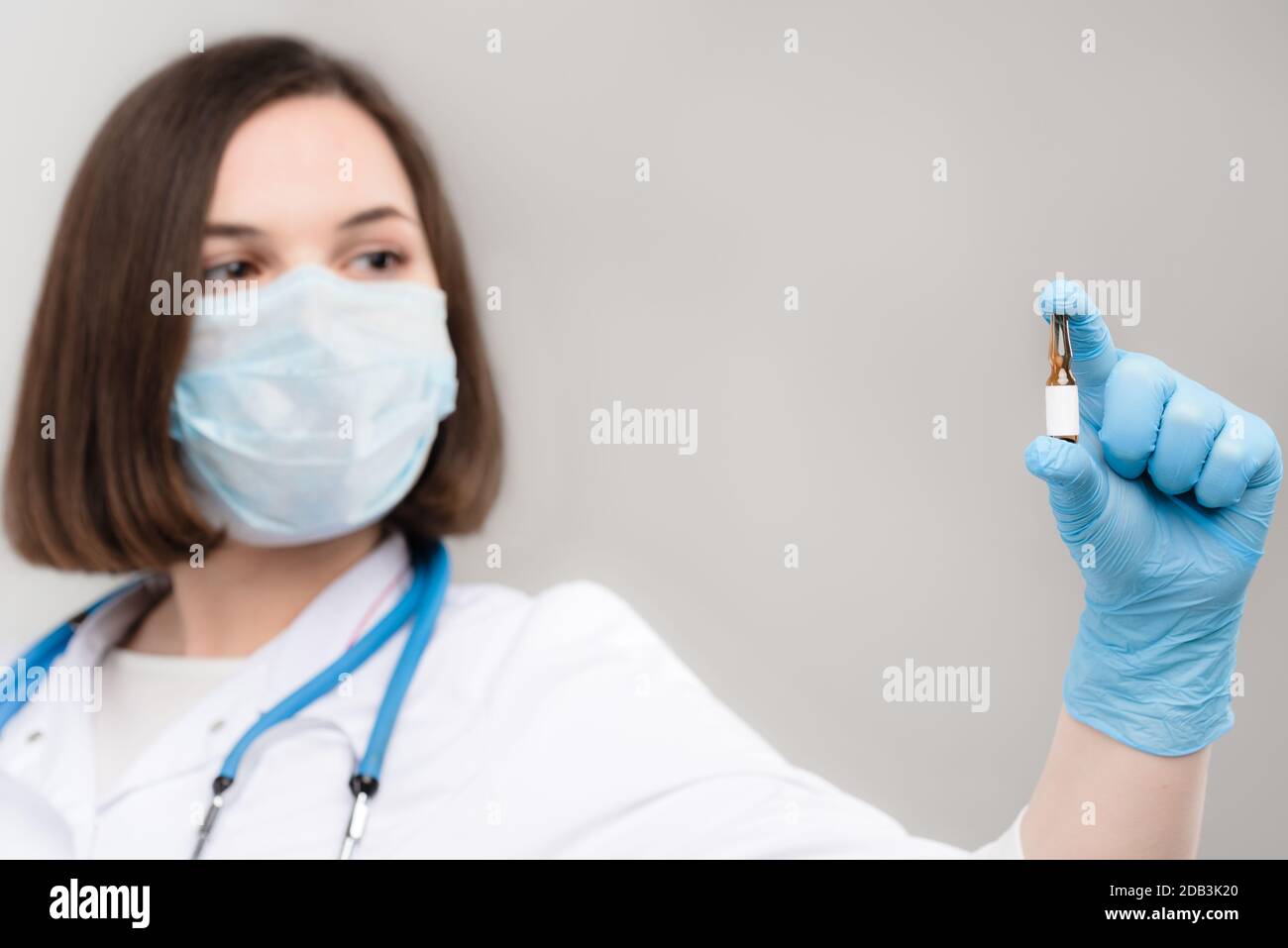 Portrait of young beautiful doctor shows drugs in hands on light ...