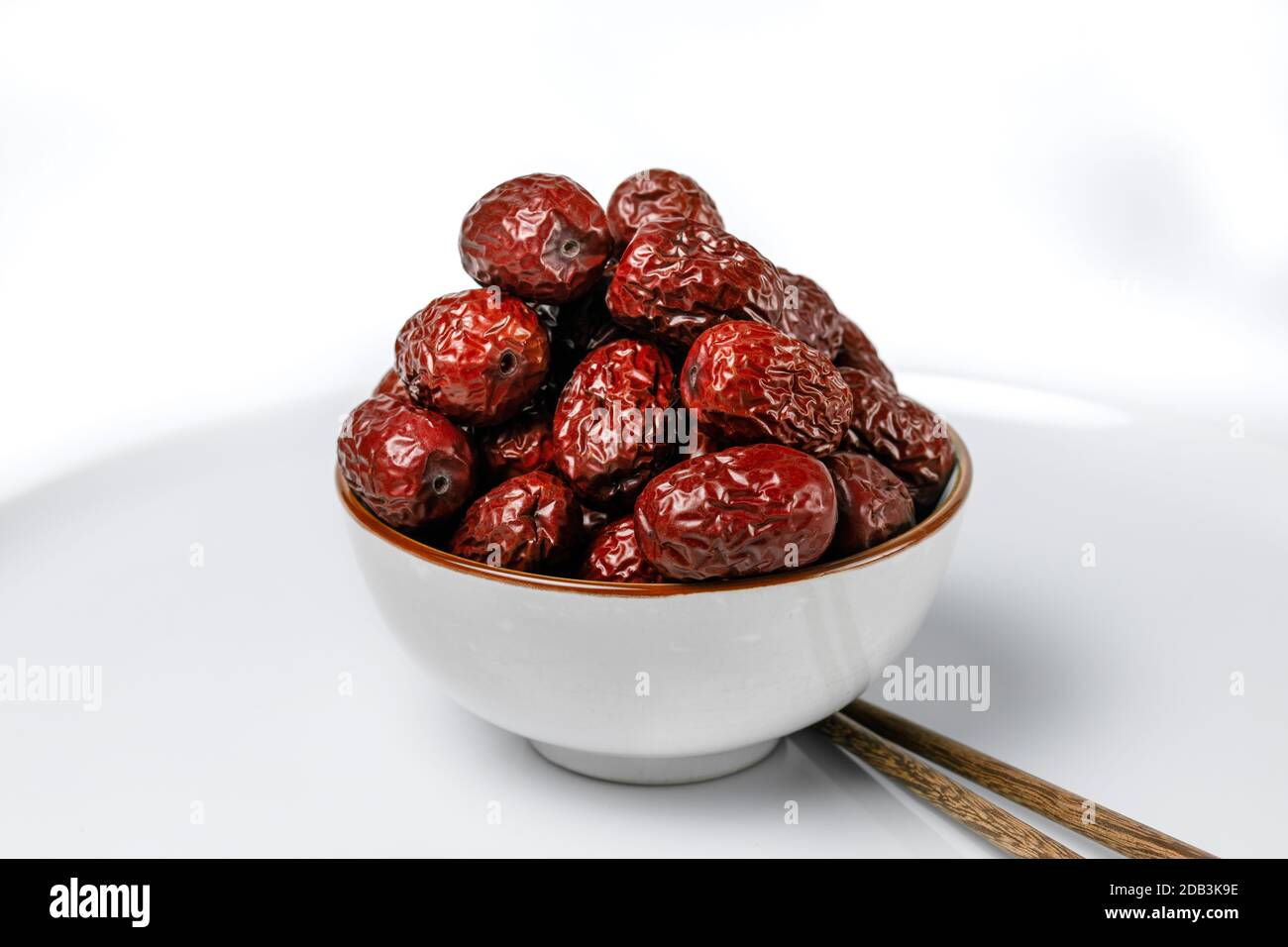 Dried Chinese dates in a ceramic cup on a white background with Chinese ...