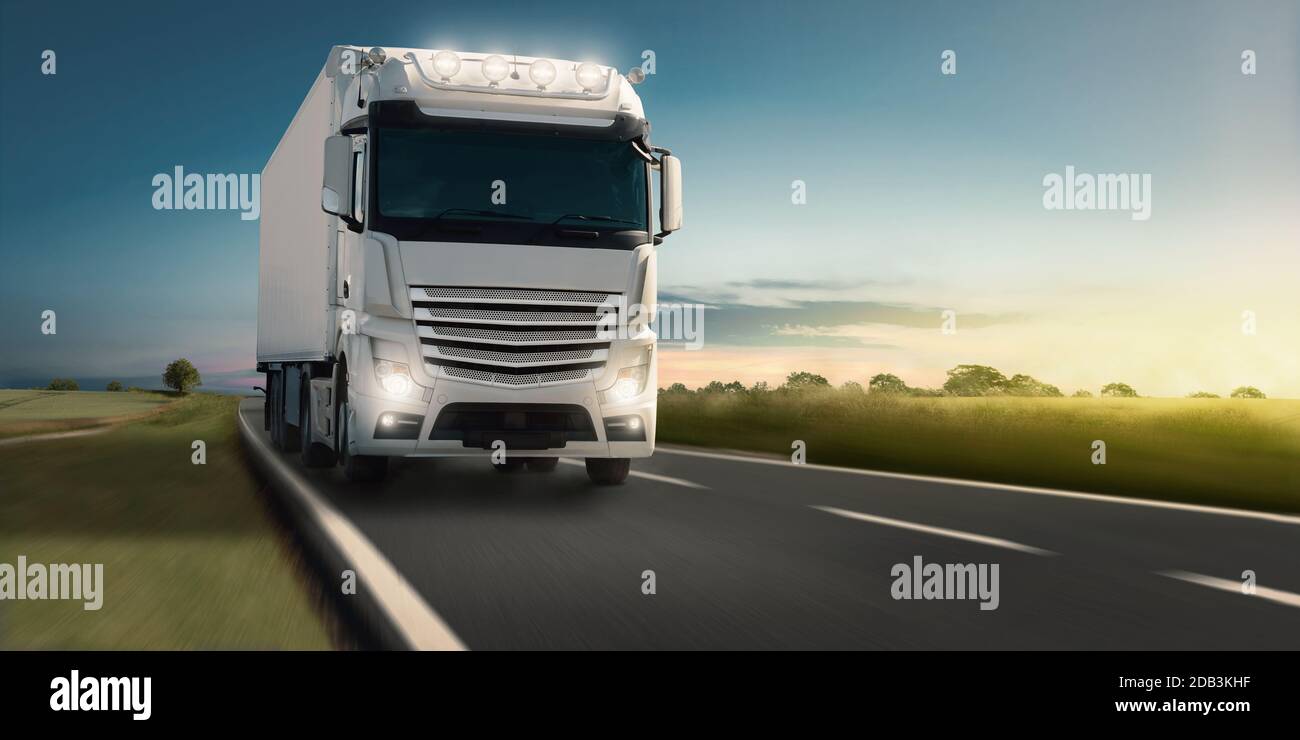 Fast moving truck in full lighting at sunset in a beautiful landscape ...