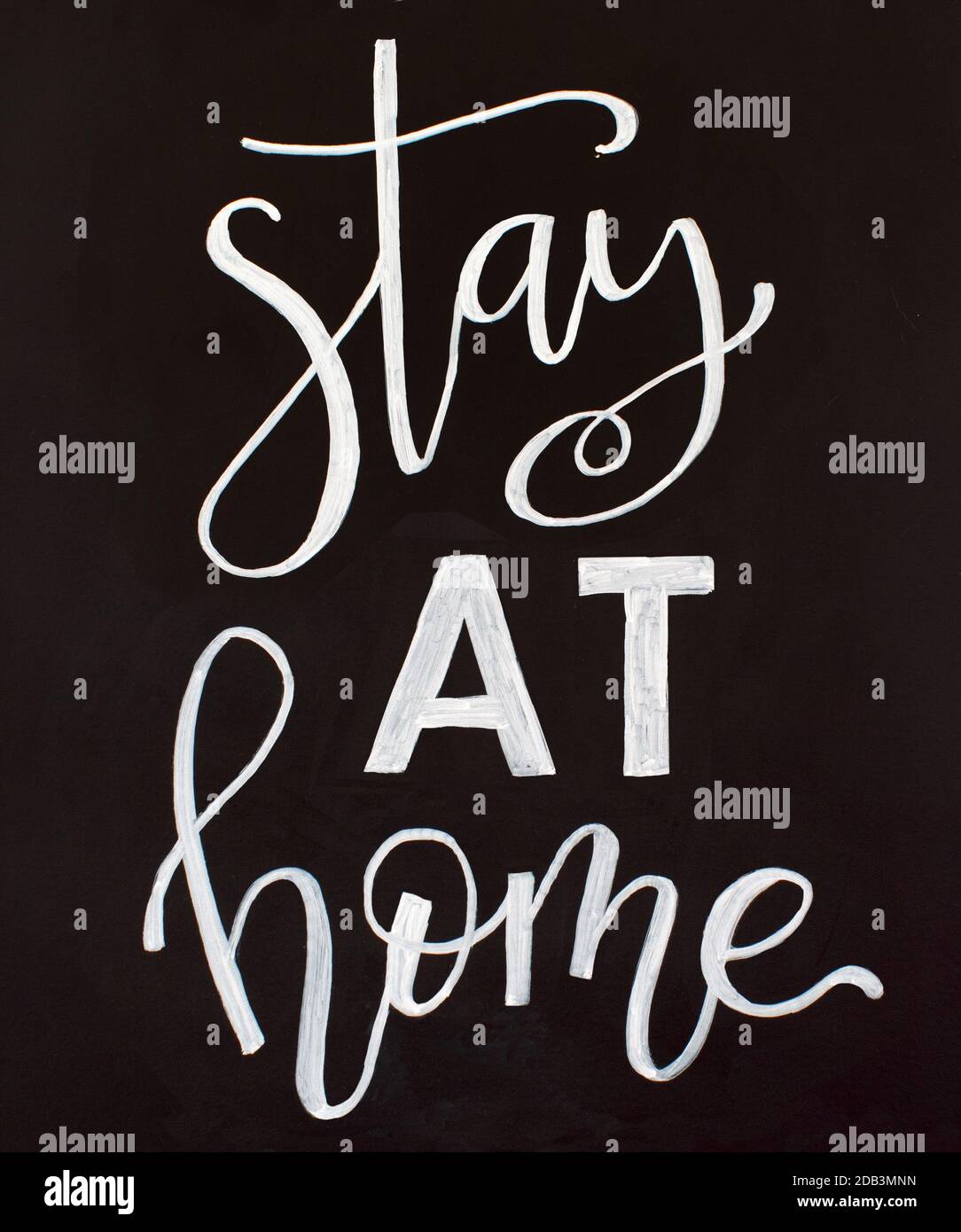 Chalk inscription STAY AT HOME on a black chalkboard. Handwritten ...