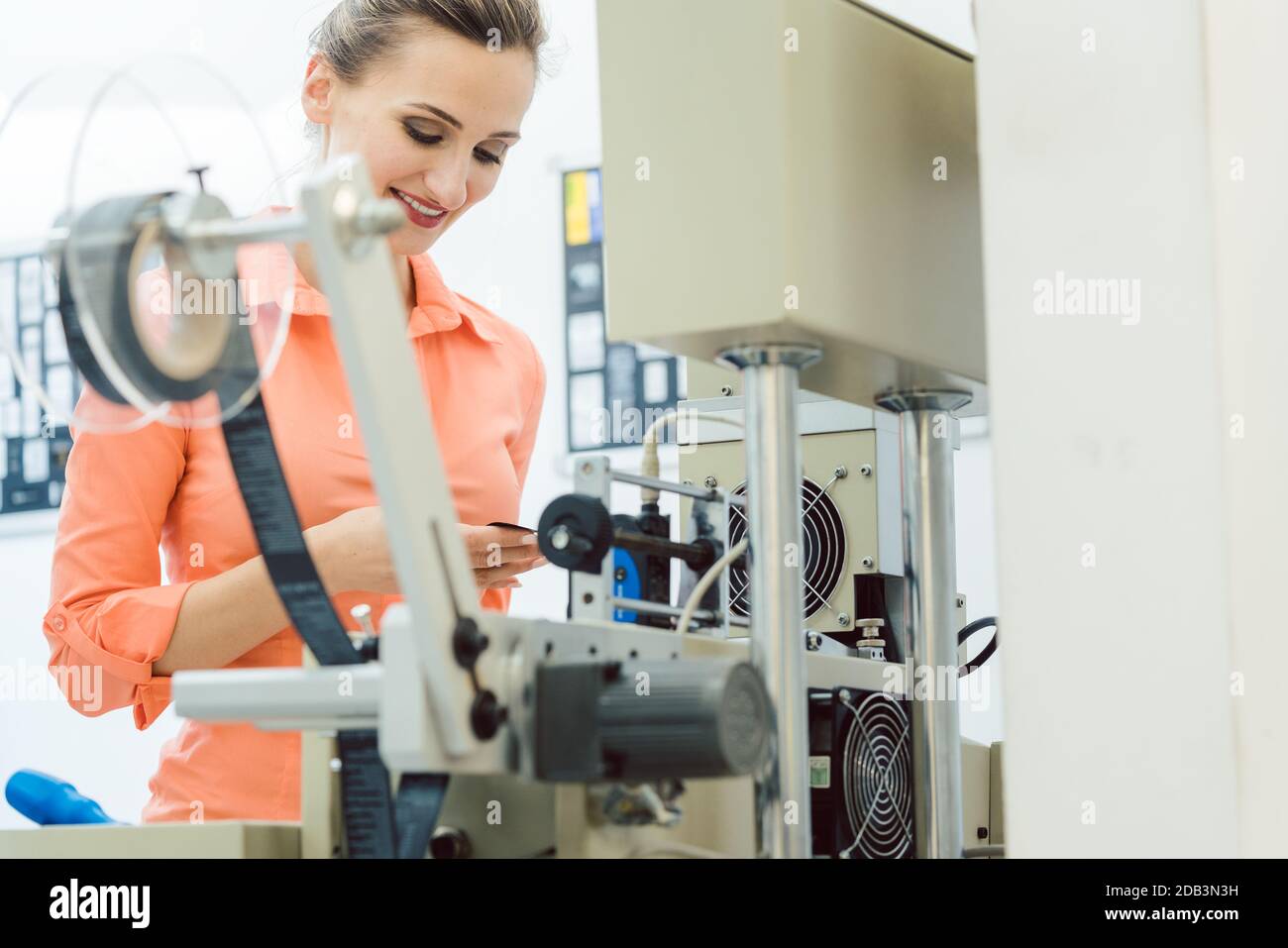 Worker woman checking textile label fresh from the printing machine ...
