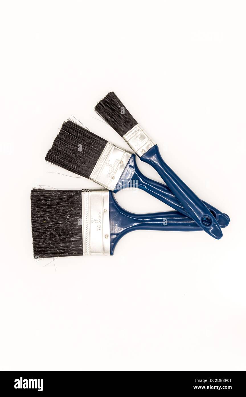Three paint brushes with blue colored handles on an isolated white ...