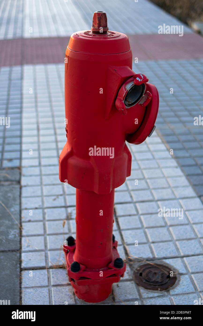 red fire hydrant installed on a city sidewalk Stock Photo - Alamy