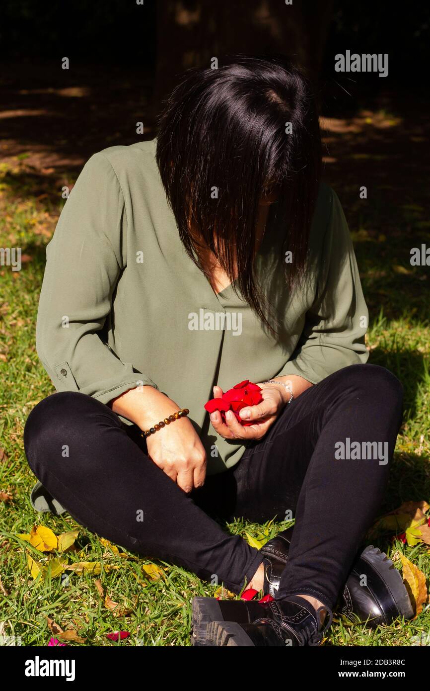 A vertical shot of attractive female throwing autumn leaves in the air ...