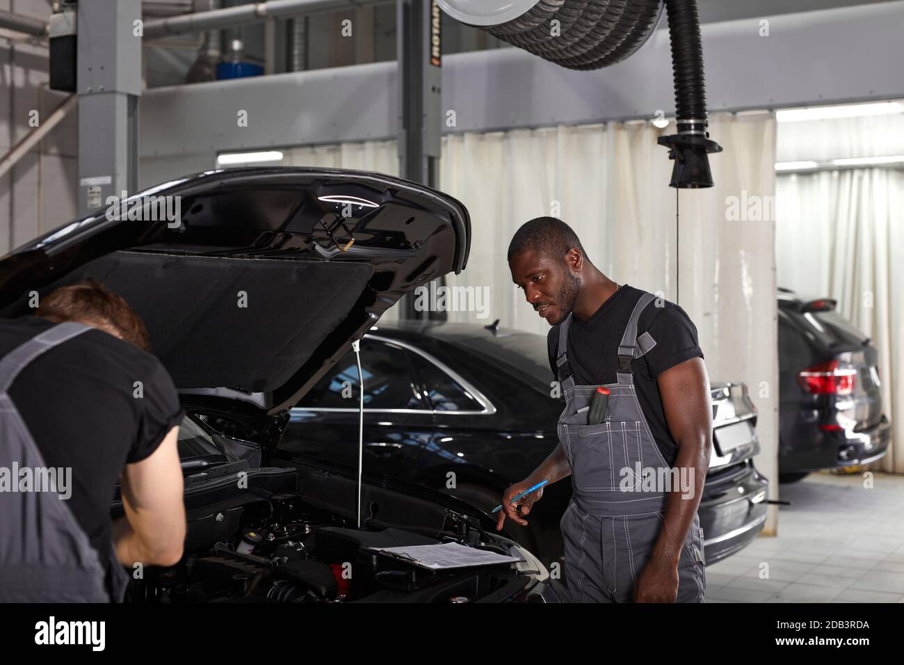 multi-ethnic team of african and caucasian men working in auto service ...