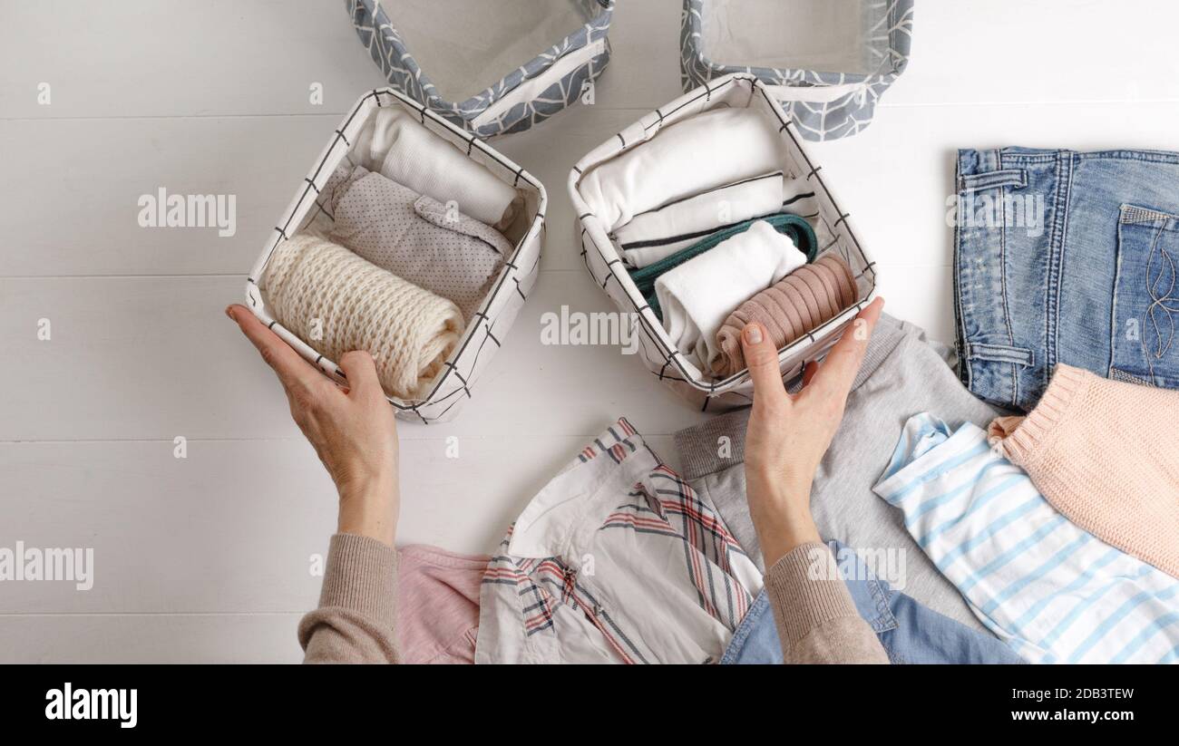 A woman folds clothes and puts them in baskets and boxes. Minimalism in ...