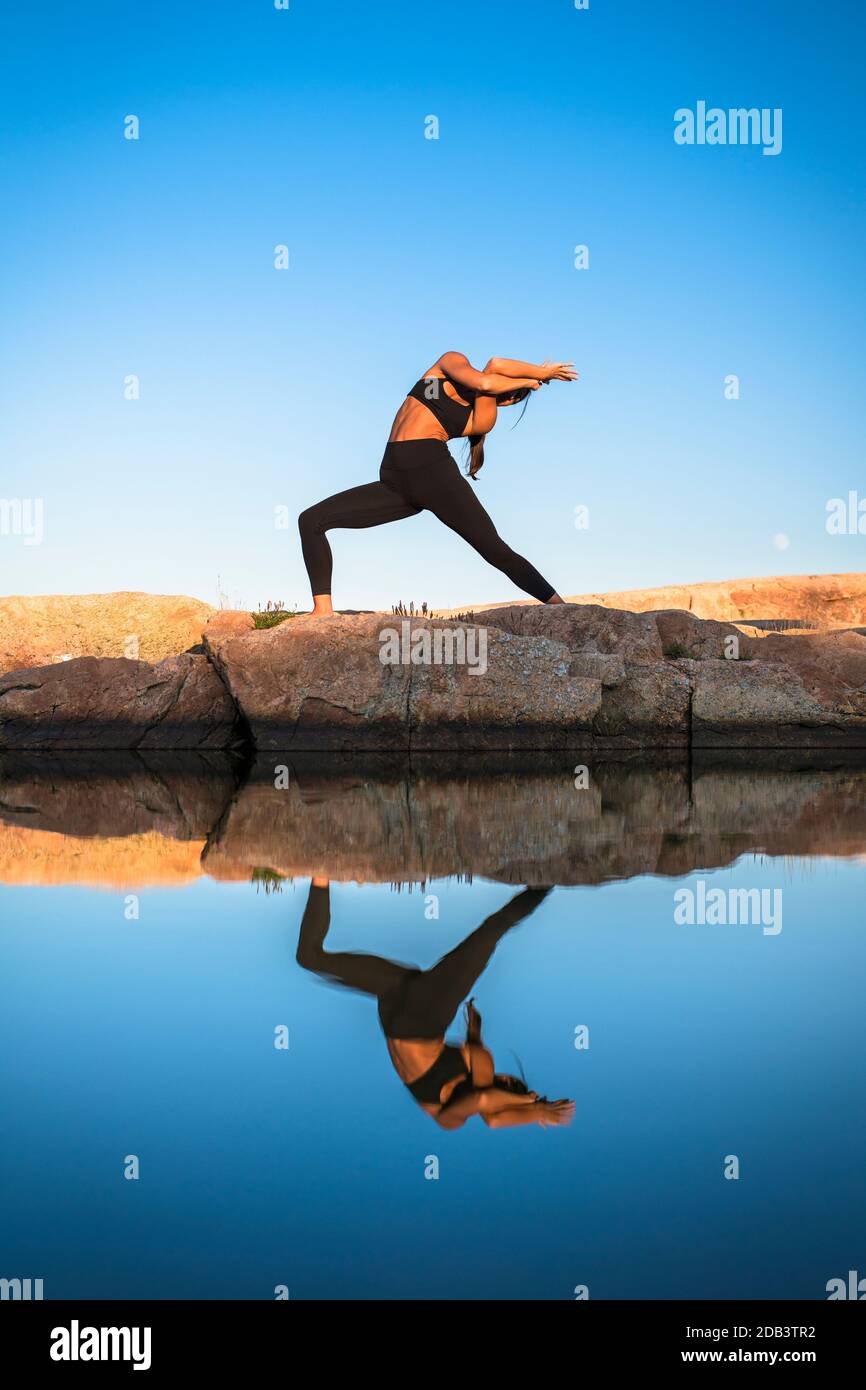 Young ethnic woman performing outdoor yoga during golden hour sunset ...