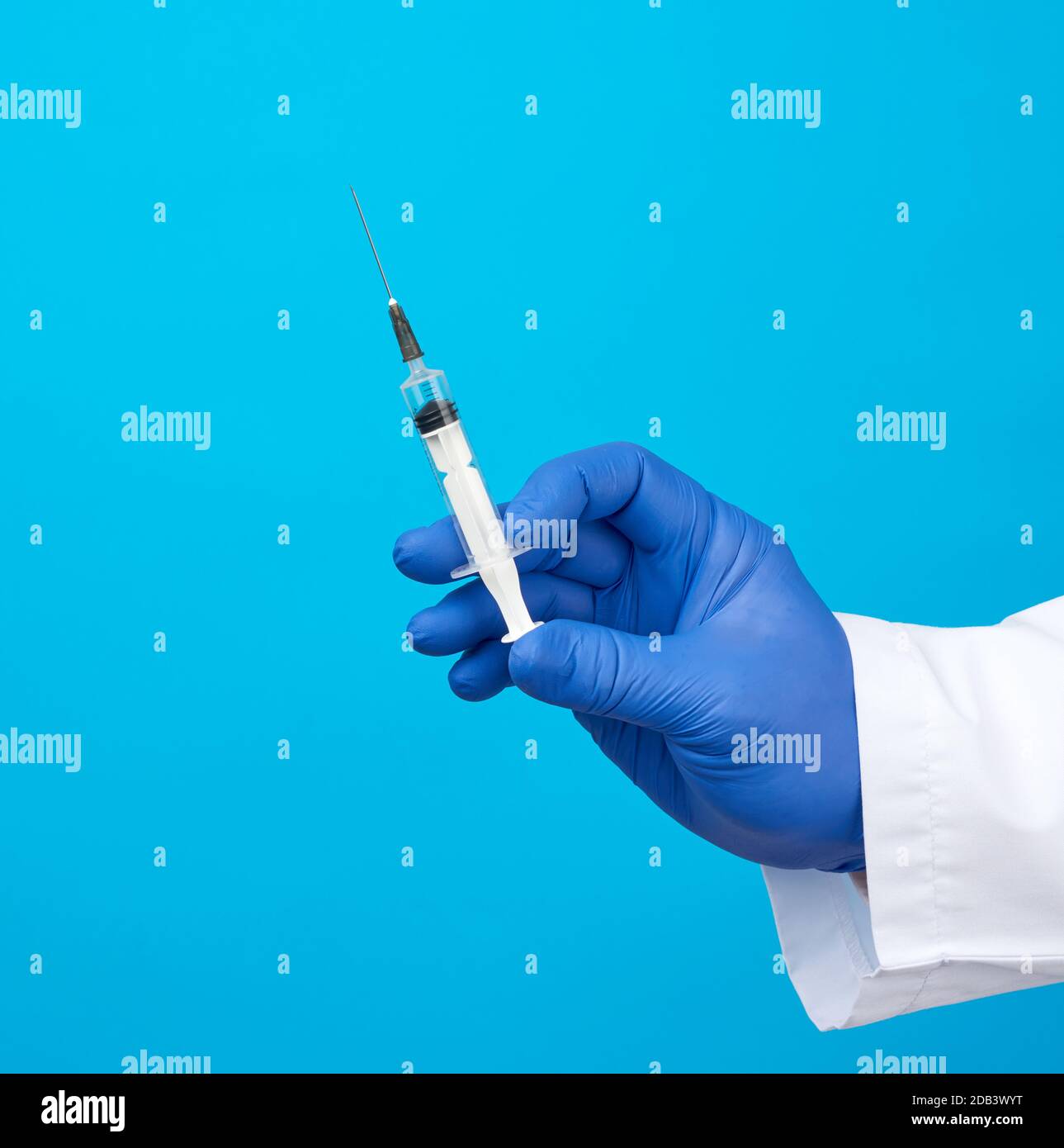 male doctor in a white coat holds a plastic syringe with a needle on a ...