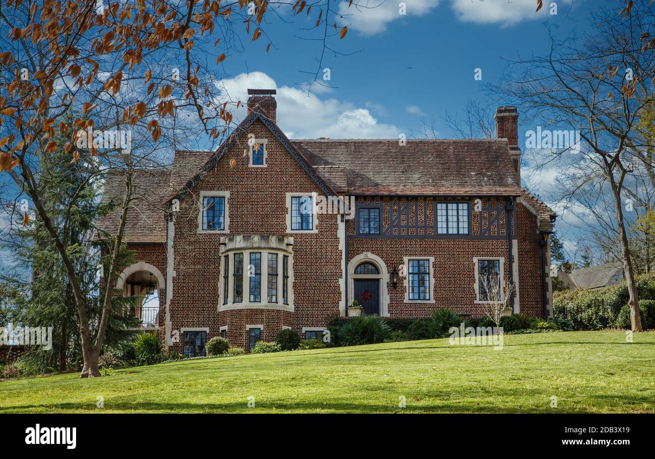 An old brick home with classic stone encased windows on a green grass ...